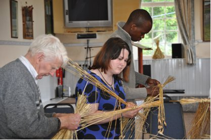 An adult partnership making traditional straw costume.